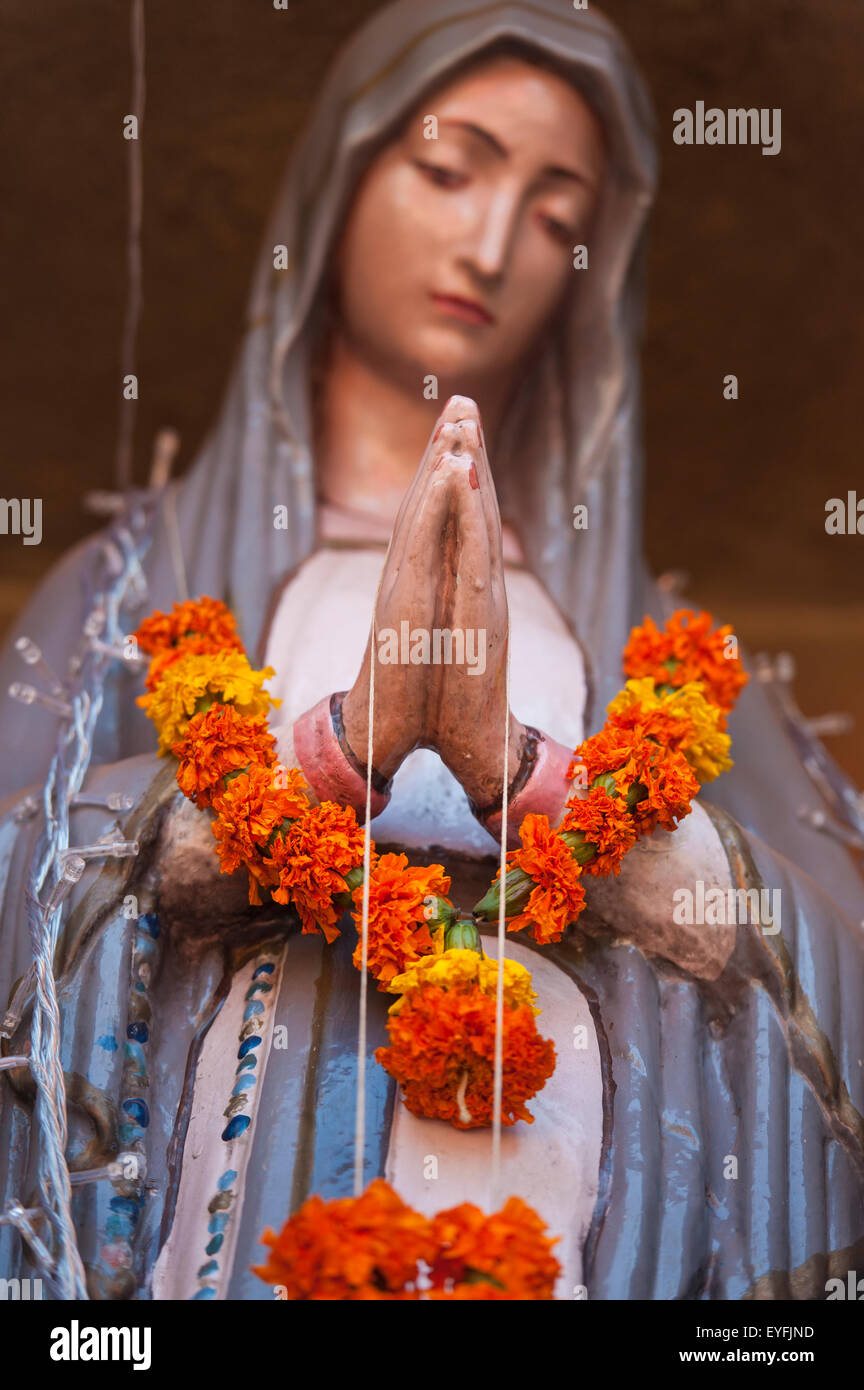 Statue of the Virgin Mary with garland of marigolds around her neck ...