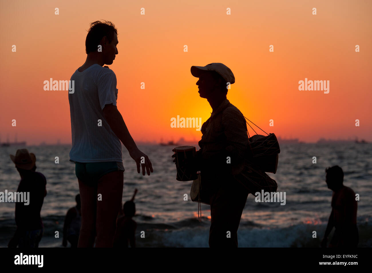Man bargaining for drums on the beach; Goa, India Stock Photo - Alamy