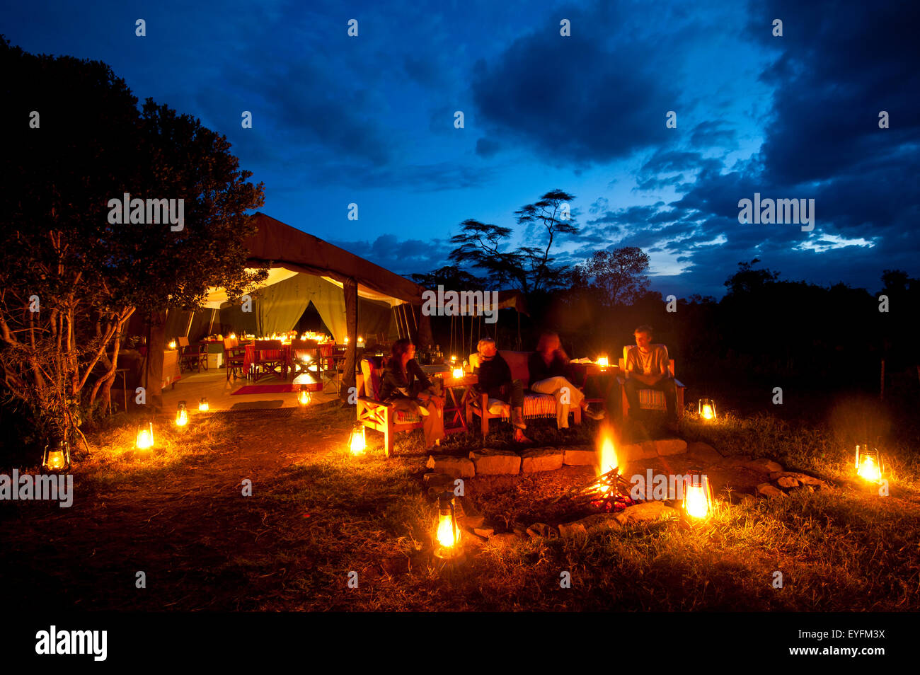 People sitting around fire at dusk in front of dining tent, Ol Pejeta ...