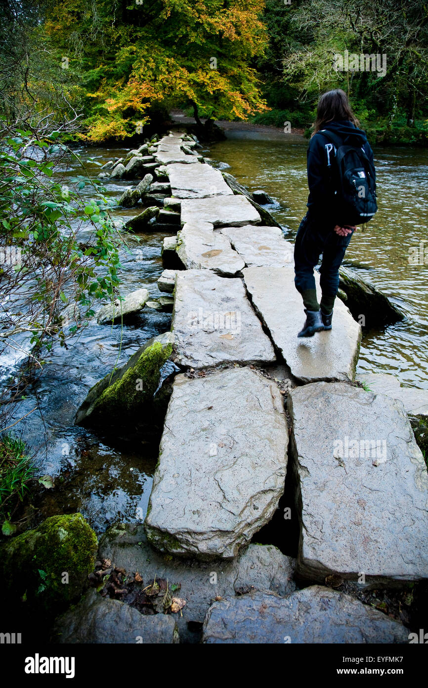 Tourist crossing The Tarr Steps, a prehistoric clapper bridge across ...