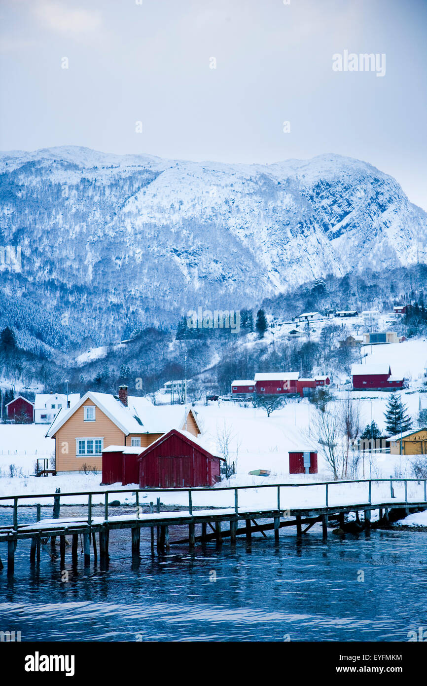 Traditional Norwegian village in the snow, jetty at side of fjord ...