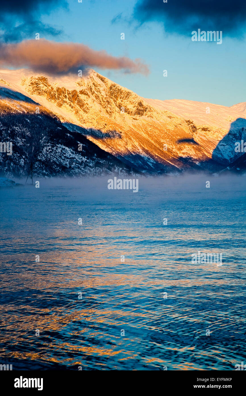 Snow covered mountains illuminated by golden sunlight at sunset ...