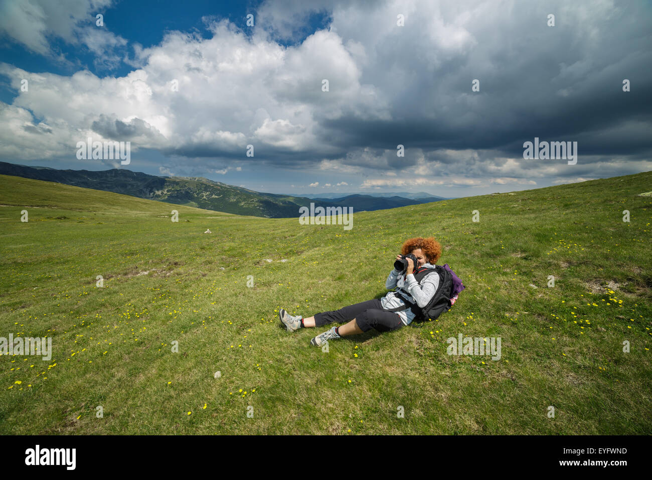 Woman hiker taking pictures with profesional camera on a mountain ...