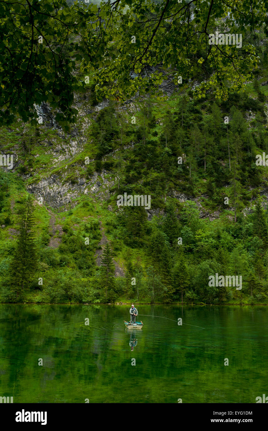 Germany, Man fly fishing from small boat in Lake Forggensee near ...