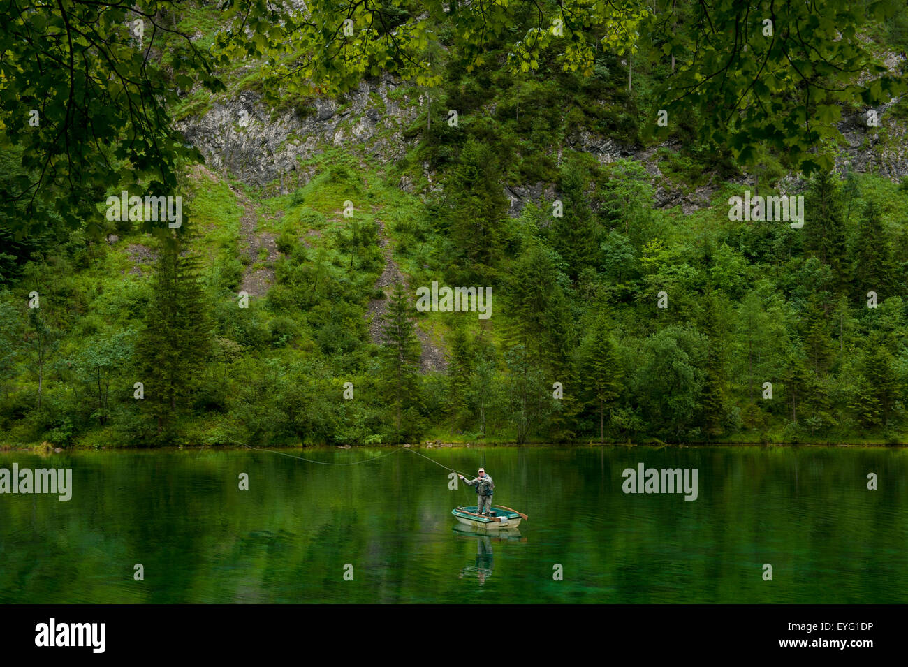 Germany, Man fly fishing from small boat in Lake Forggensee near ...
