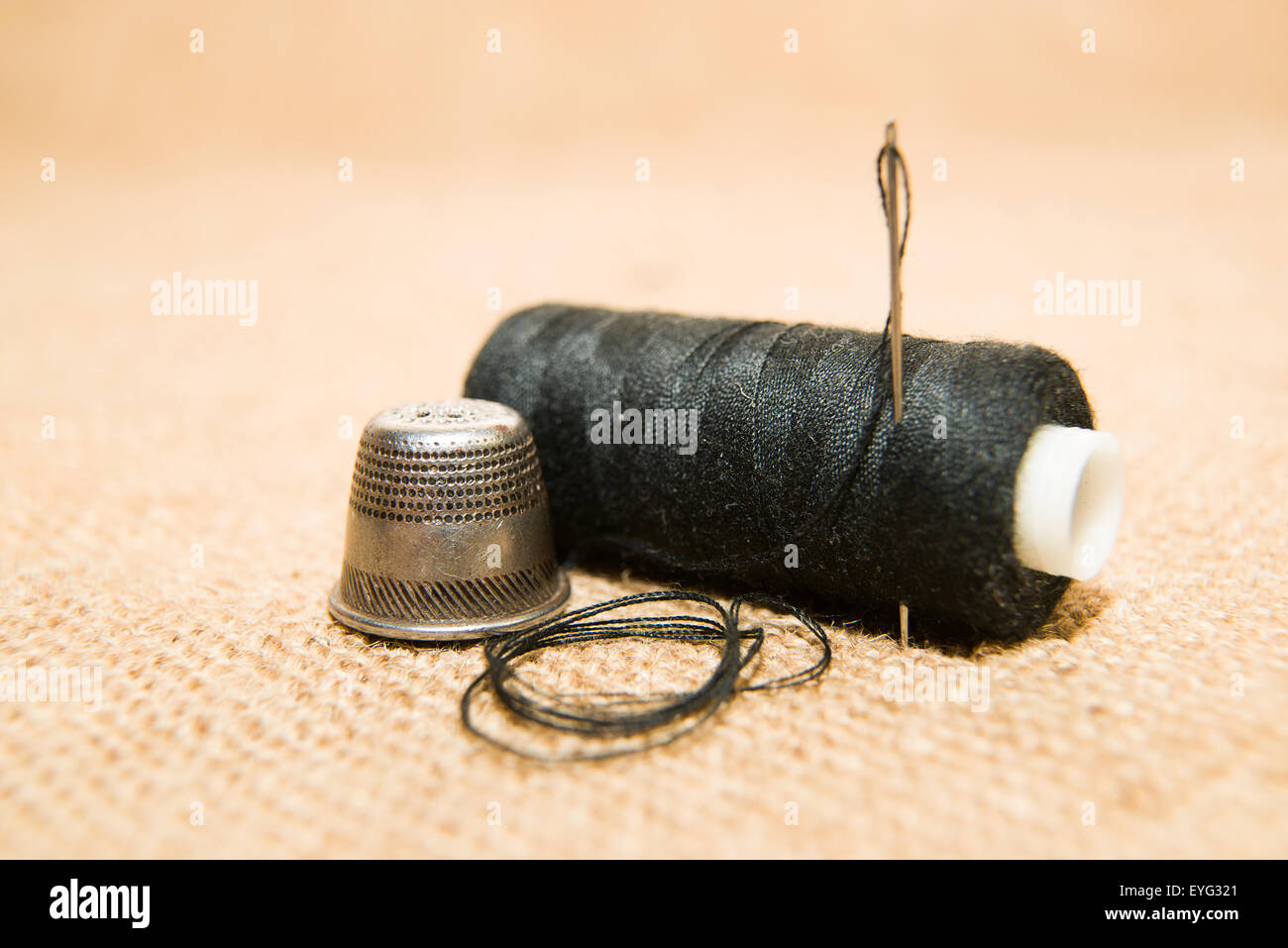 Sewing Needle, thimble and thread spool on the old cloth Stock Photo ...