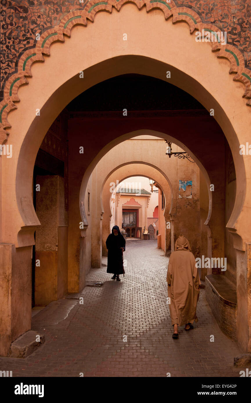 Morocco, Men walking through arched alleyway in Medina of Marrakesh ...
