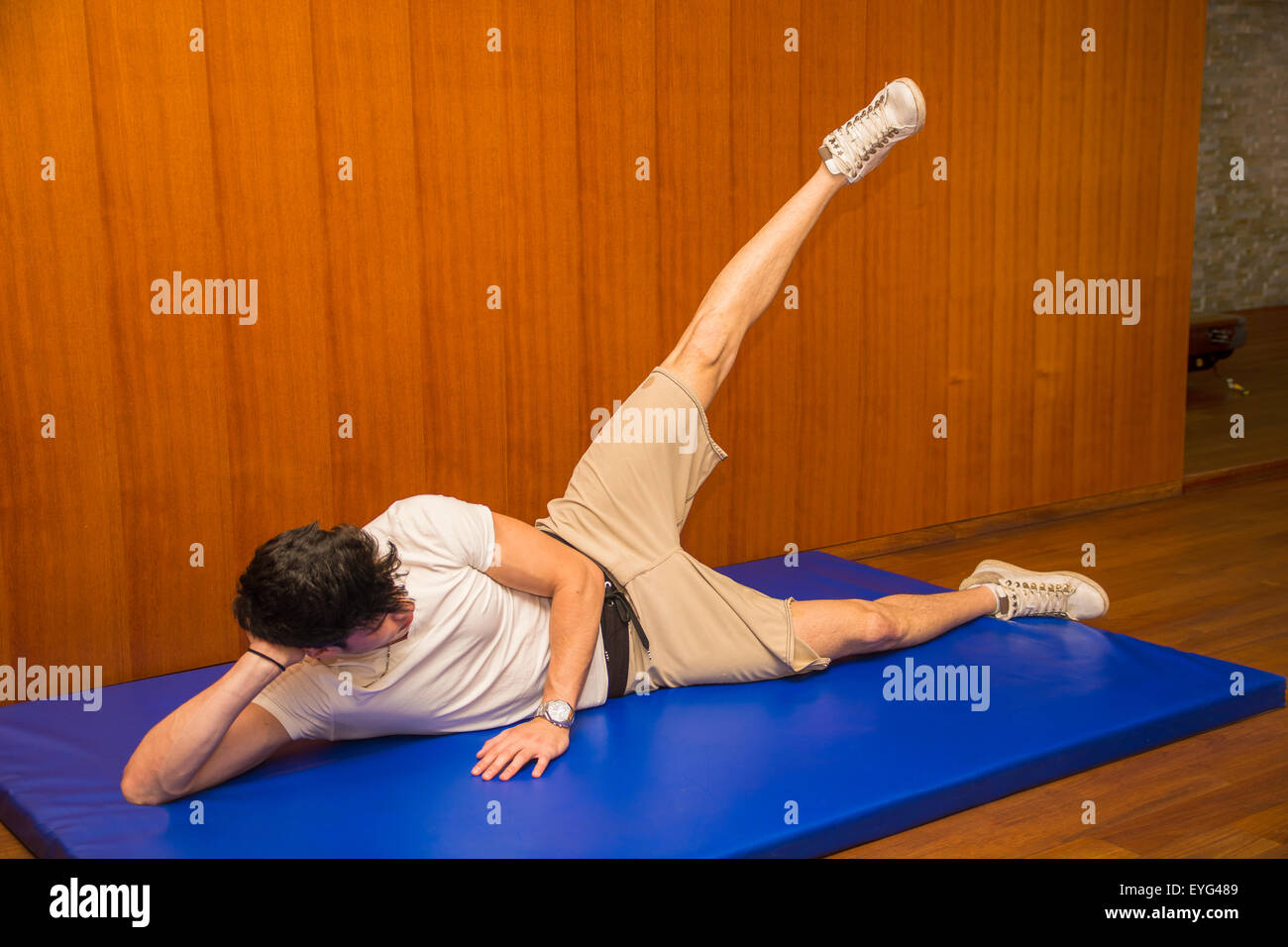 Attractive young man during workout in gym, lifting leg while laying on ...