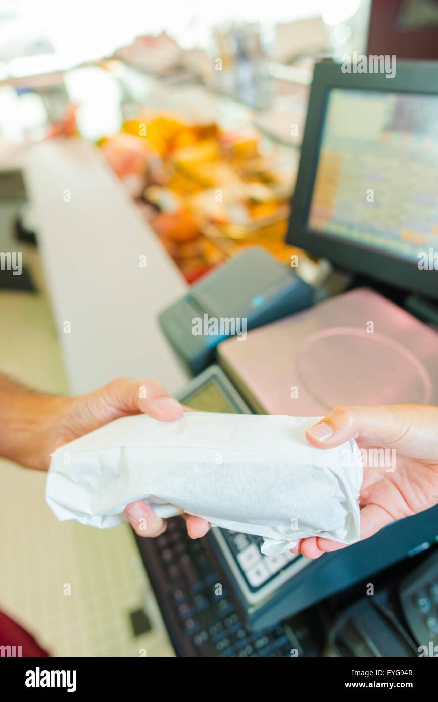 Butcher handing wrapped meat to customer Stock Photo - Alamy