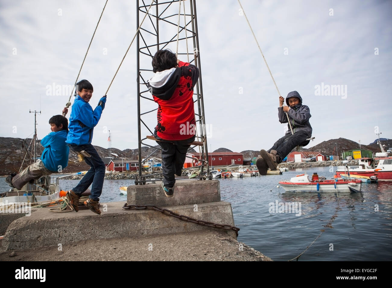 Denmark, Greenland, Kids swinging over water in harbour; Paamiut Stock ...