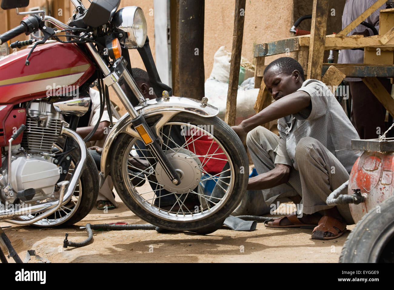 Niger, Air Region, Housa mechanic fixing motorbike in back street ...