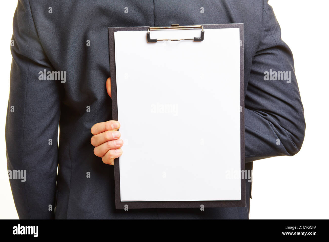 Business man holding empty clipboard with white paper behind his back ...