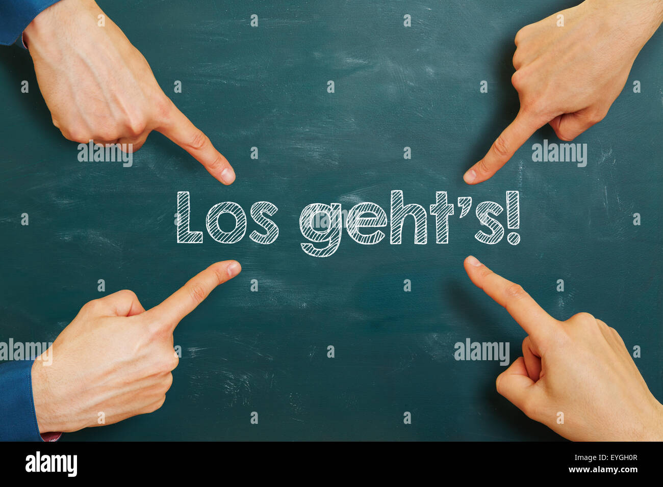 German slogan "Los geht's" (let's go) on a chalkboard with hands ...