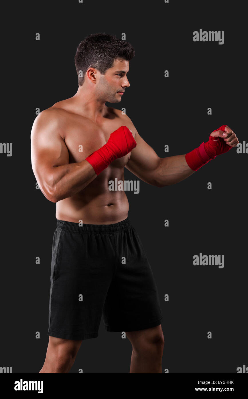 Portrait of a muscular man practicing body combat against a dark ...