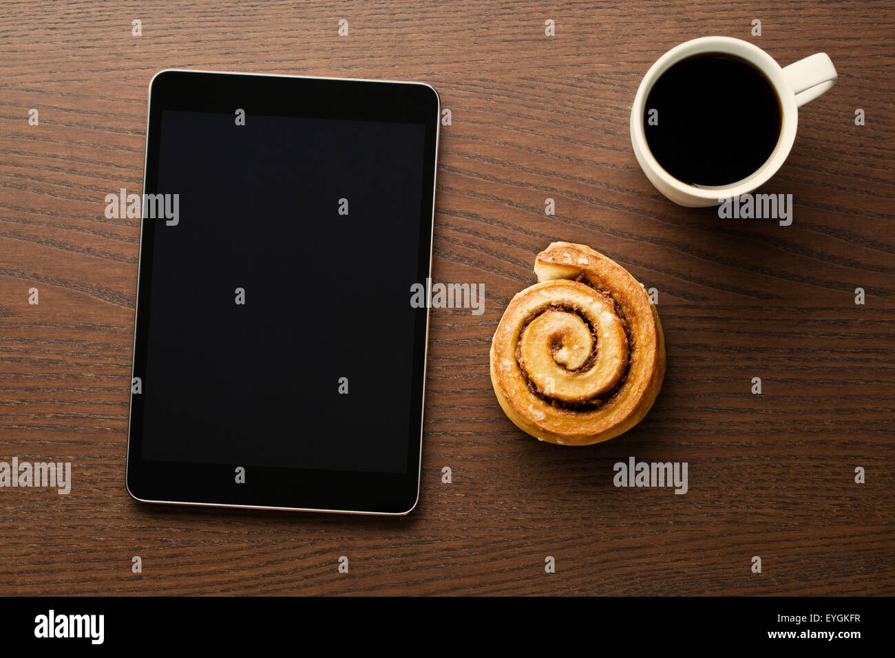 Cinnamon roll, cup of coffee and computer tablet. Business breakfast ...