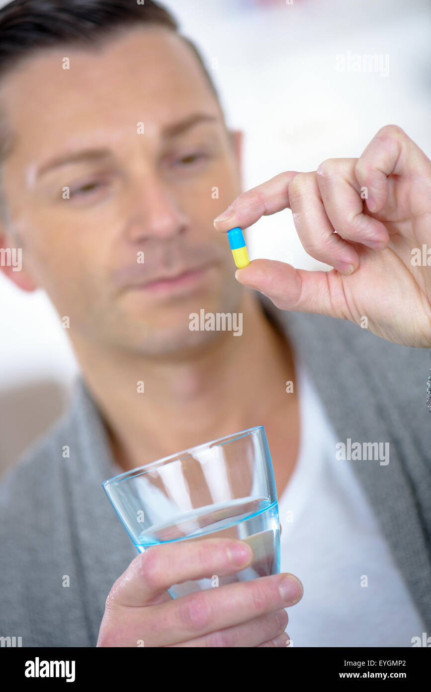 Man holding capsule tablet and glass of water Stock Photo - Alamy