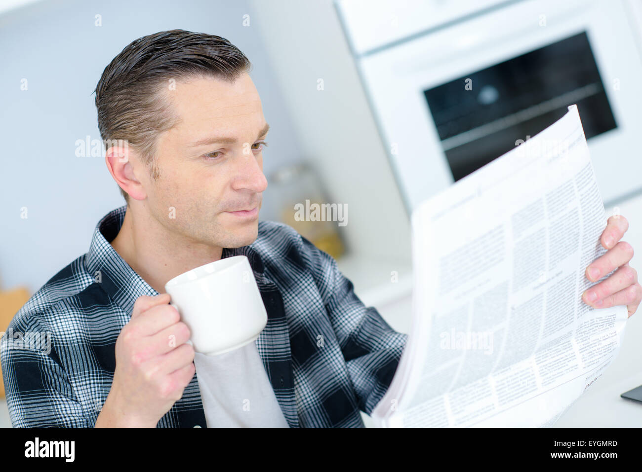 Man reading paper holding cup Stock Photo - Alamy
