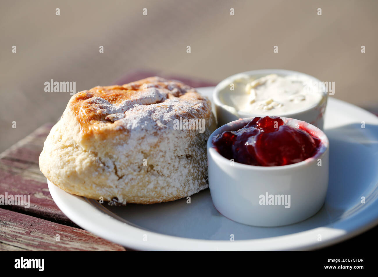 A freshly prepared scone with jam and cream, an English cream tea ...