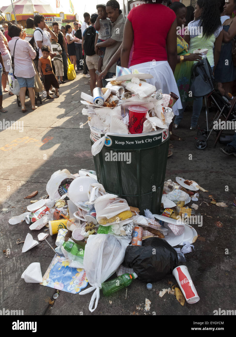 Refuse from fast food meals overflows garbage pail and litters sidewalk ...