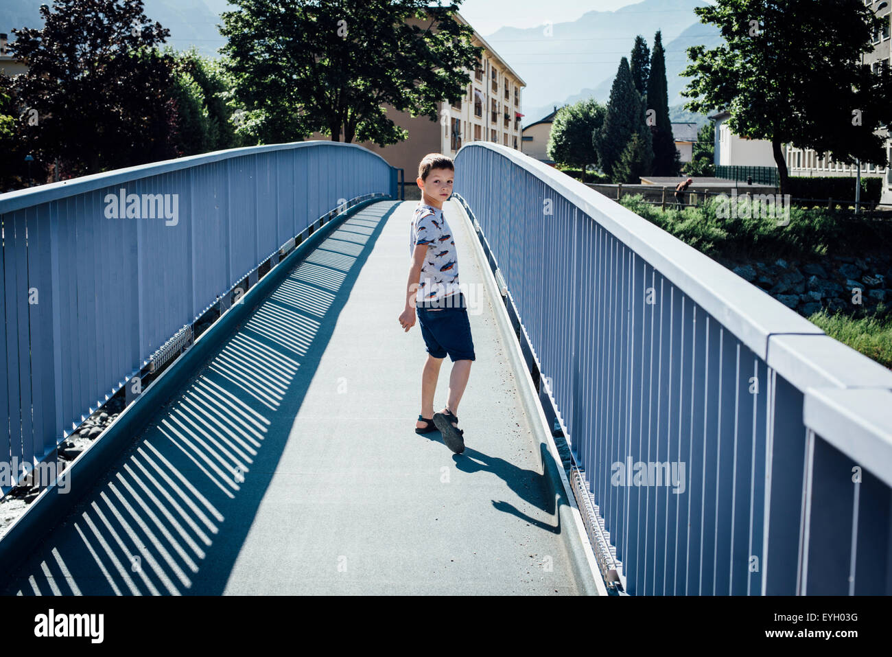 Primary school boy walking over bridge looking back Stock Photo - Alamy