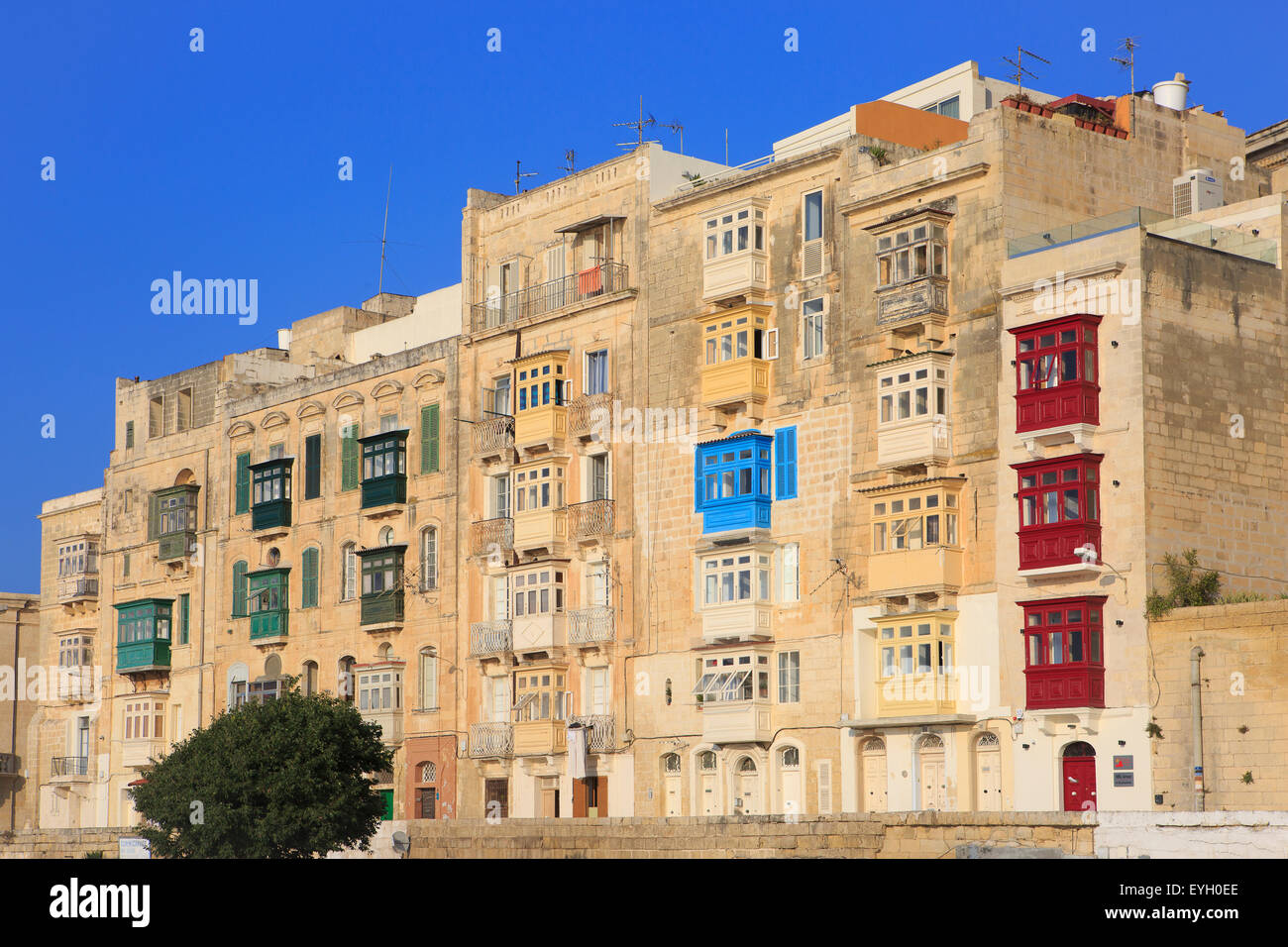 Limestone apartments with colorful traditional closed wooden balconies ...