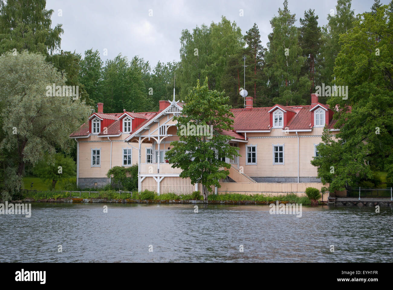 Beige house with a roof of red tiles on the lake, in the evening, near ...