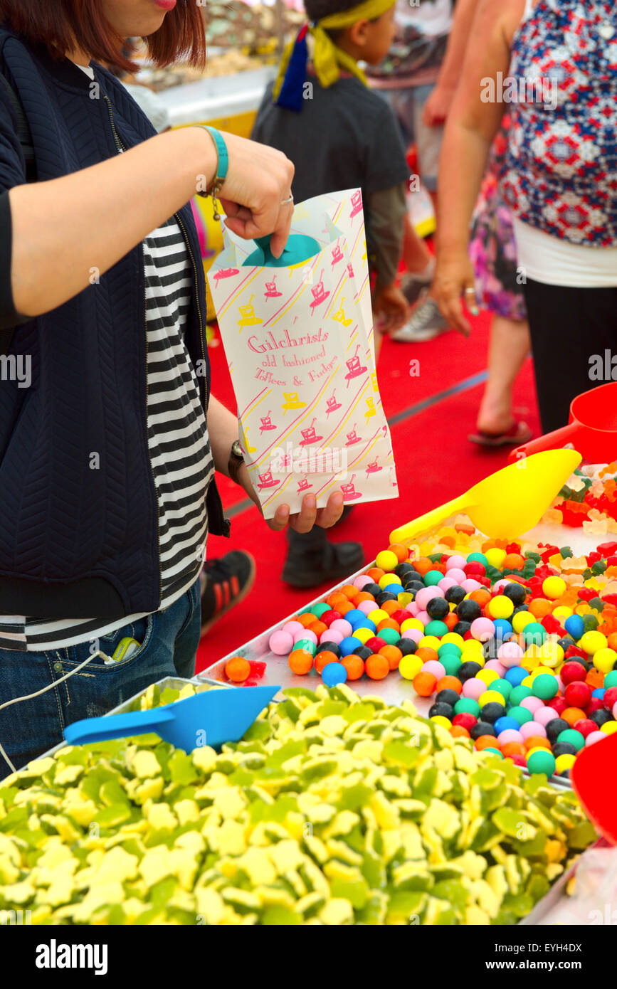 Woman customers selecting sweets from pick and mix selections of ...