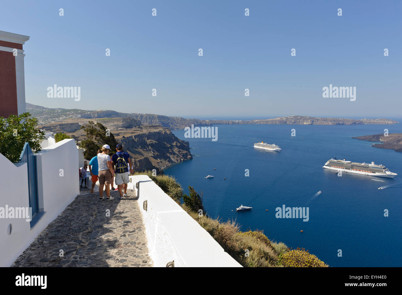 Tourists walking along the narrow cobbled walkway on the caldera ...