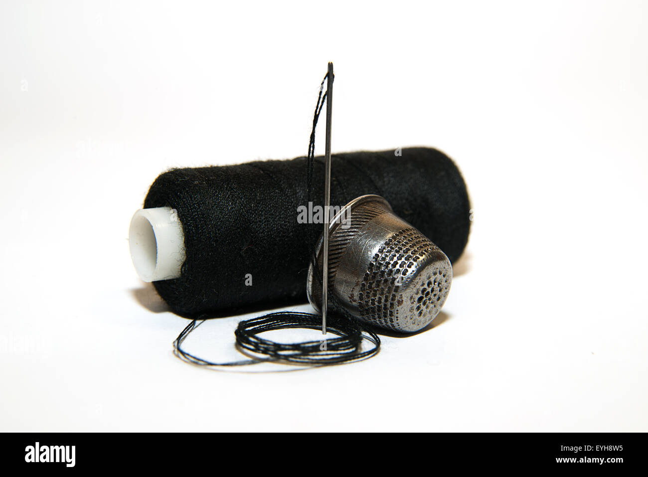 Sewing Needle, thimble and thread spool on a white background Stock ...