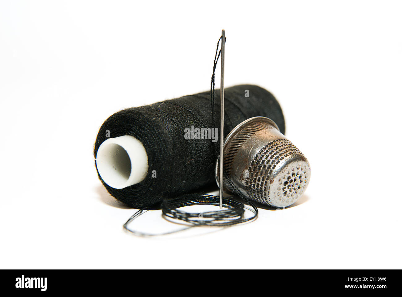 Sewing Needle, thimble and thread spool on a white background Stock ...