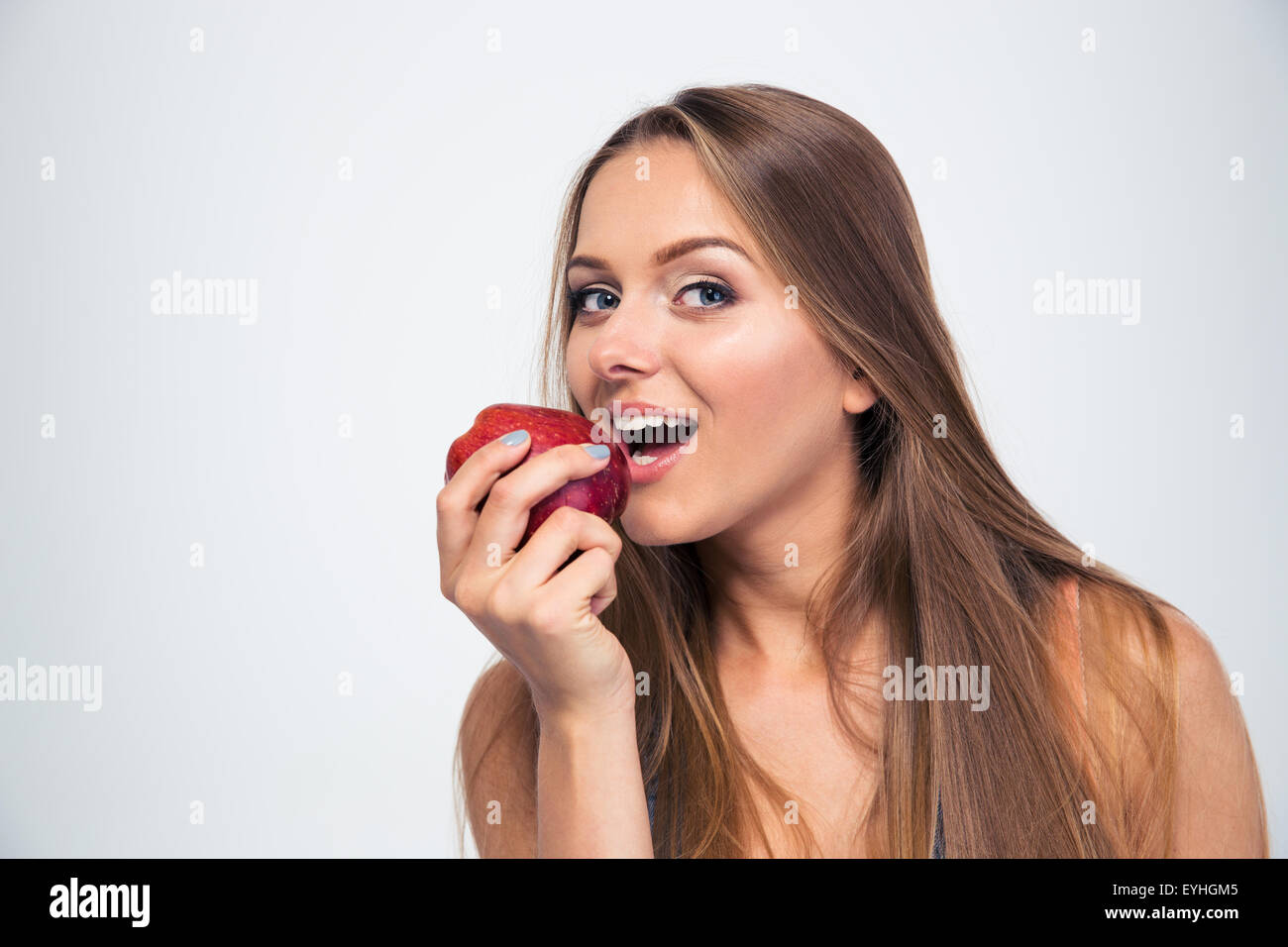 Portrait of a young girl biting apple isolated on a white background ...