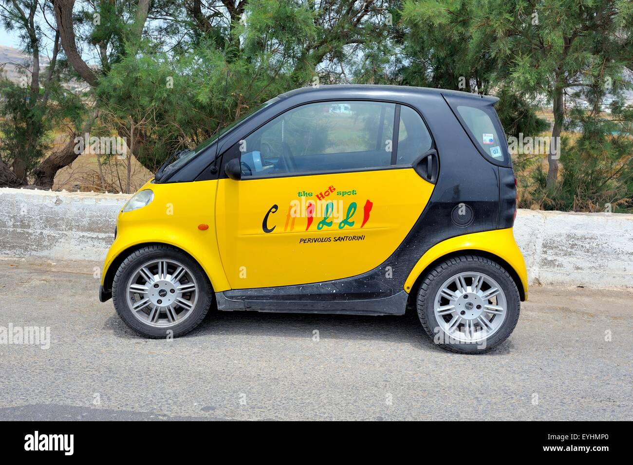 A yellow and black Smart Car advertising a restaurant on it's doors ...