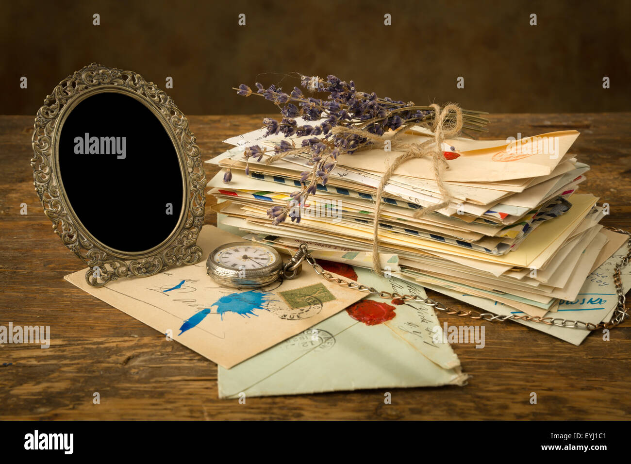 Empty antique picture frame and a pile of old letters on a wooden table ...