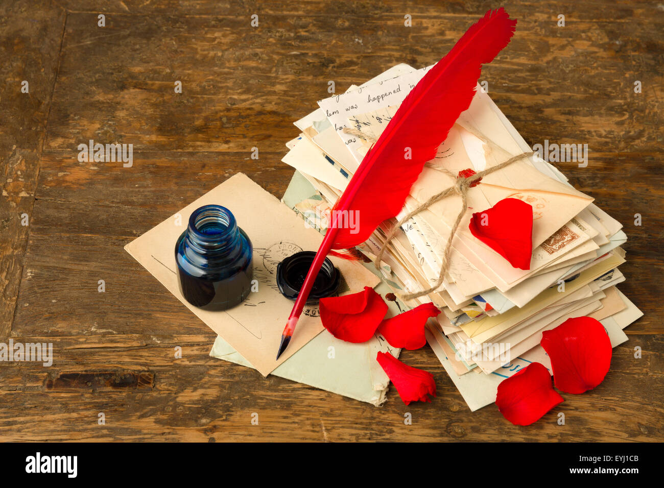 Red quill feather and ink well lying on an old table with nostalgic ...