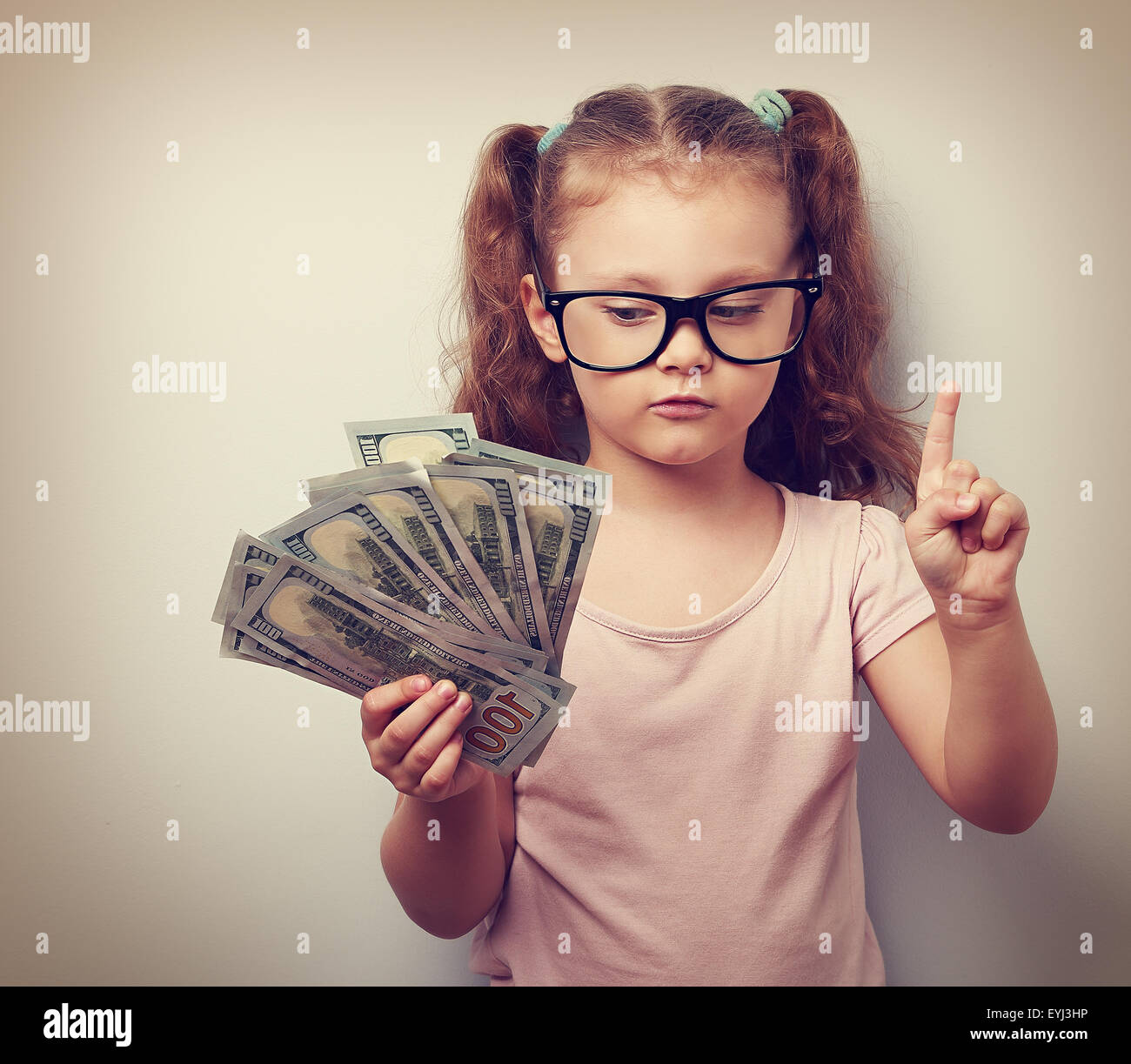 Small kid girl holding dollars and have an plan how earning much money ...