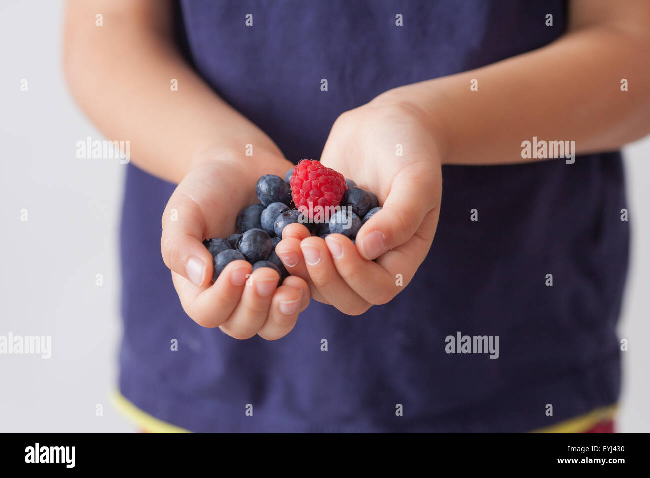 Child, holding raspberries and blueberries in his hands, isolated on ...