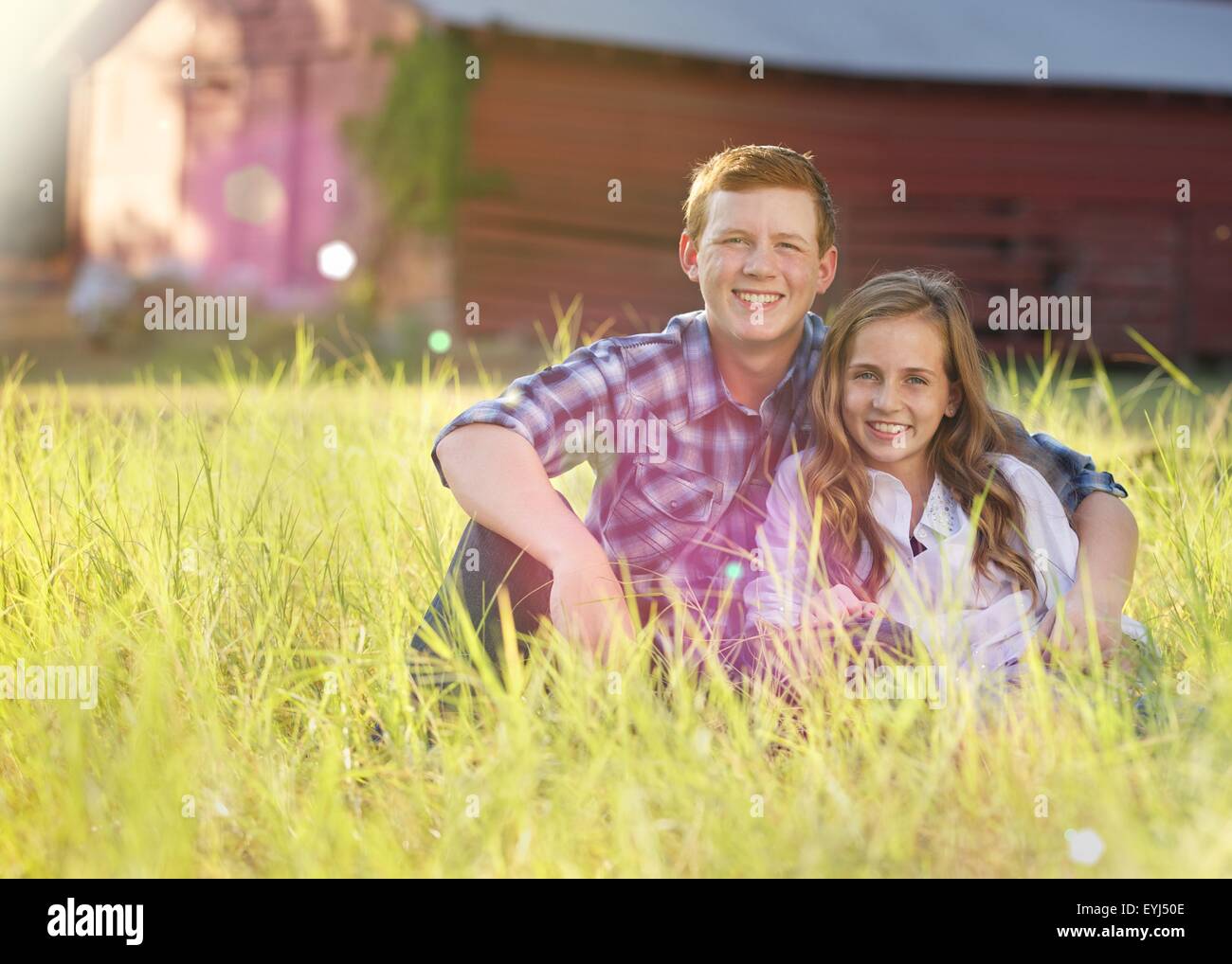 Brother and sister on a farm in front of classic red barn Stock Photo ...