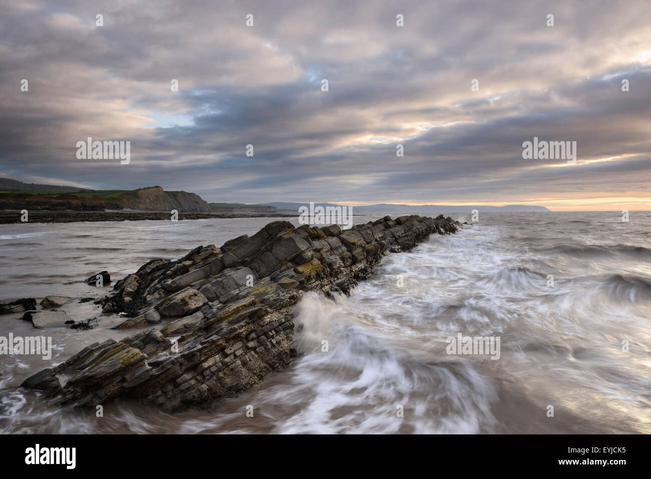 The incoming tide rushing along an outcrop of rock in the sea at Kilve ...