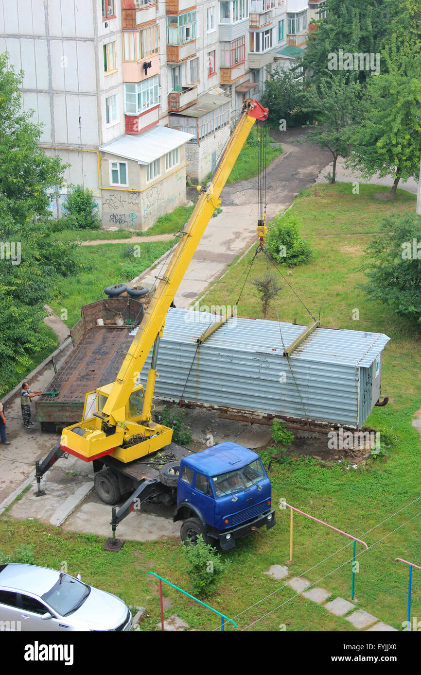 truck with hoisting crane loading the wagon in the yard of dormitory ...