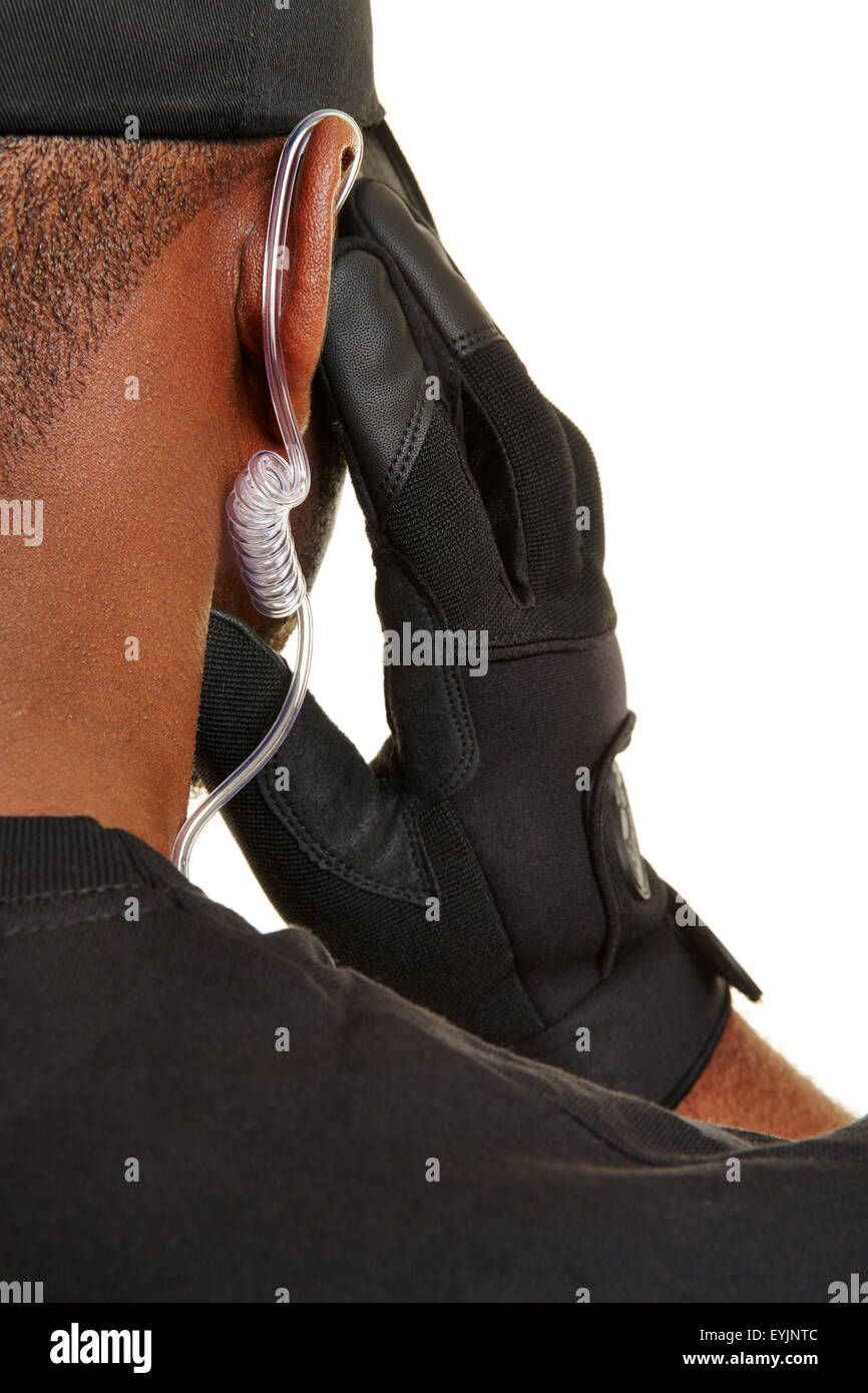 Security guard holding hand to headset in his ear Stock Photo - Alamy