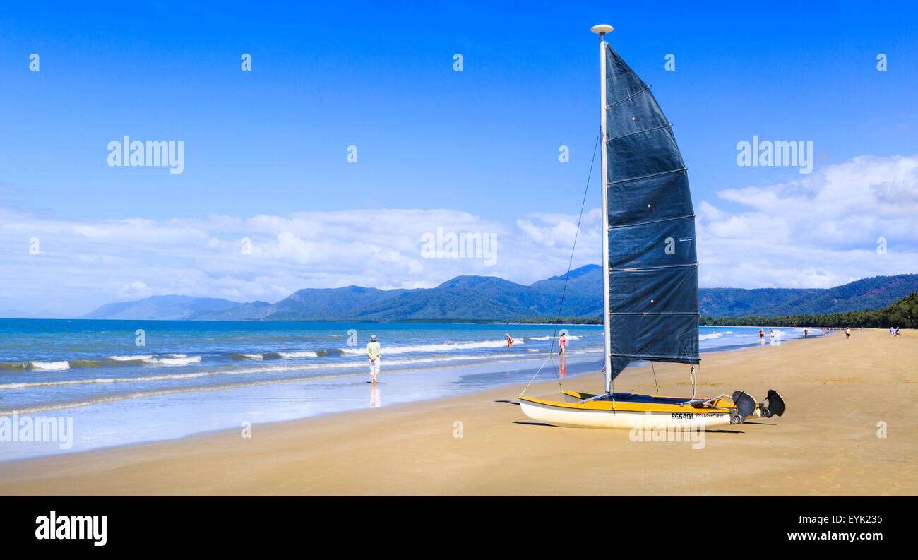 A catamaran sloop dinghy with a sail on the shores of Four Mile Beach ...