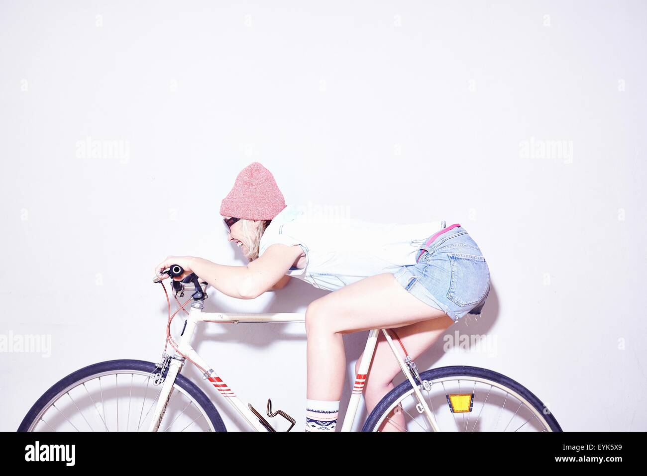 Studio shot of young woman leaning forward on bicycle Stock Photo - Alamy