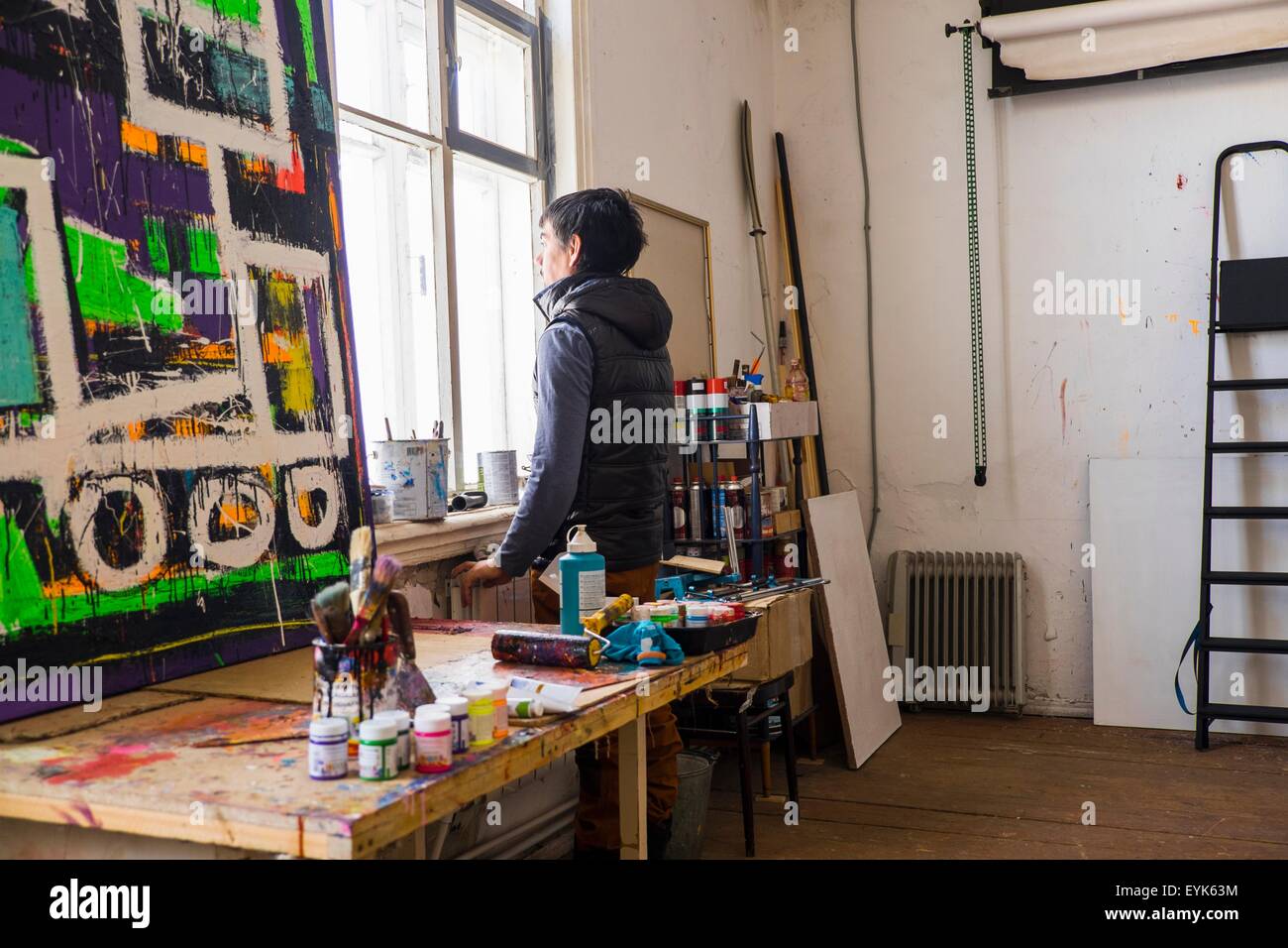 Male artist staring out of studio window Stock Photo - Alamy