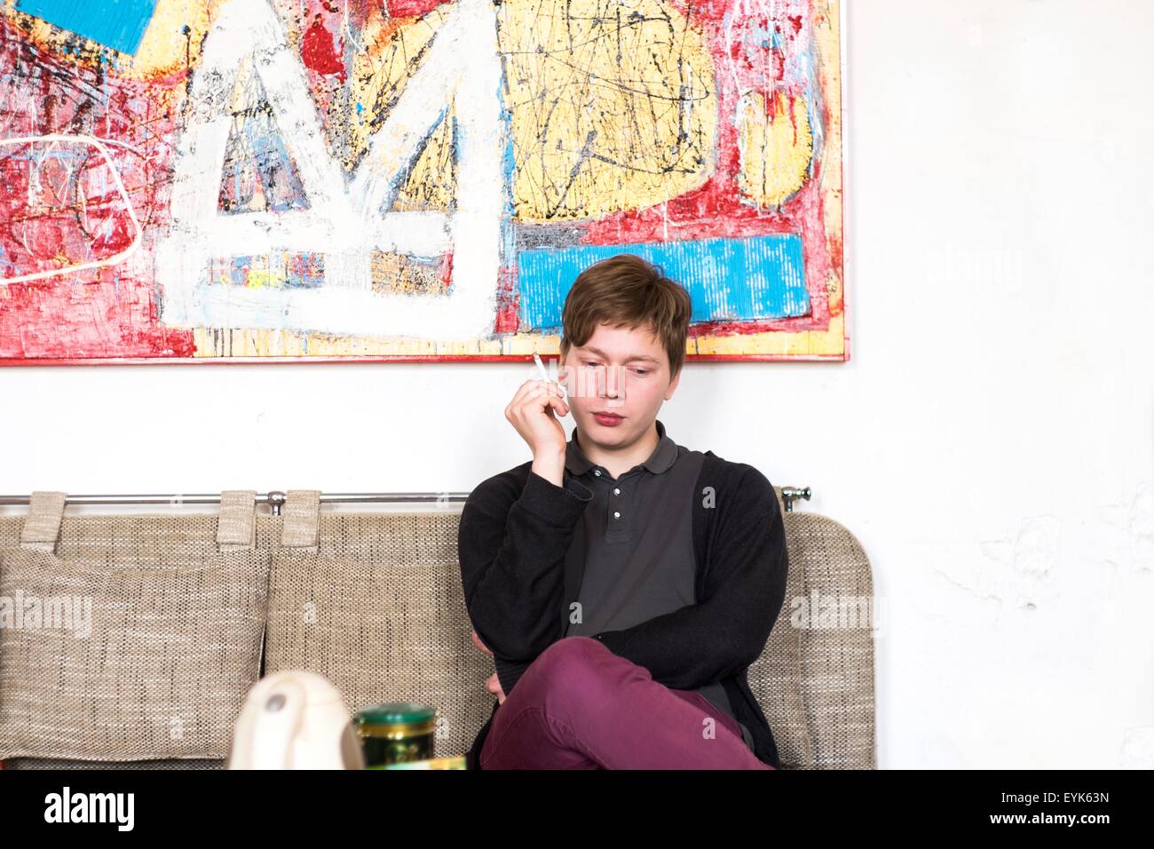 Male artist smoking cigarette whist sitting on studio sofa Stock Photo ...