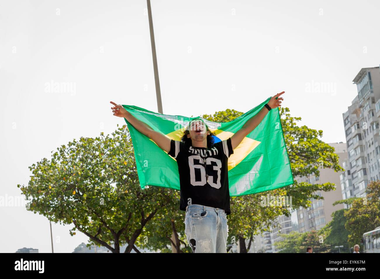 Young man holding up Brazilian flag, Copacabana, Rio De Janeiro, Brazil ...