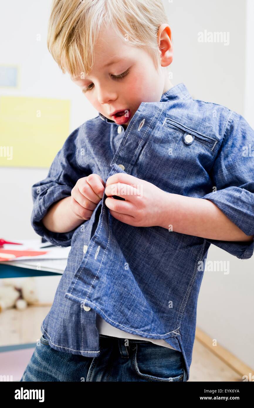 Boy buttoning shirt at home Stock Photo - Alamy