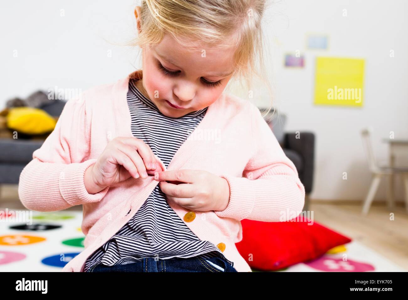 Girl buttoning cardigan Stock Photo - Alamy