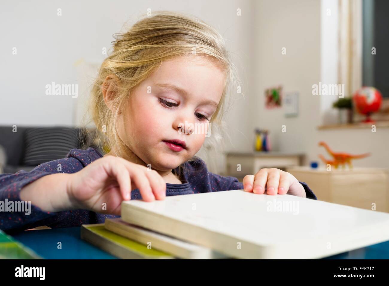 Girl arranging square blocks on table Stock Photo - Alamy
