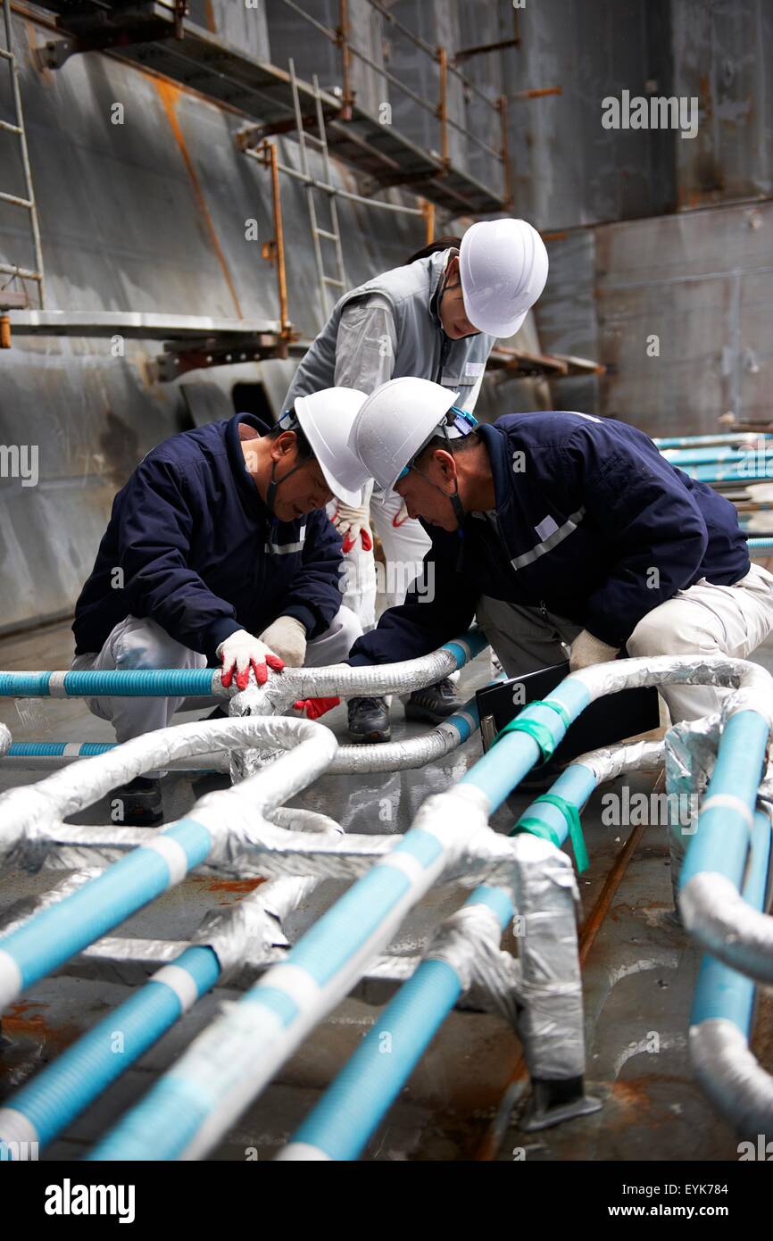 Workers checking pipework on container ship at shipyard, GoSeong-gun ...