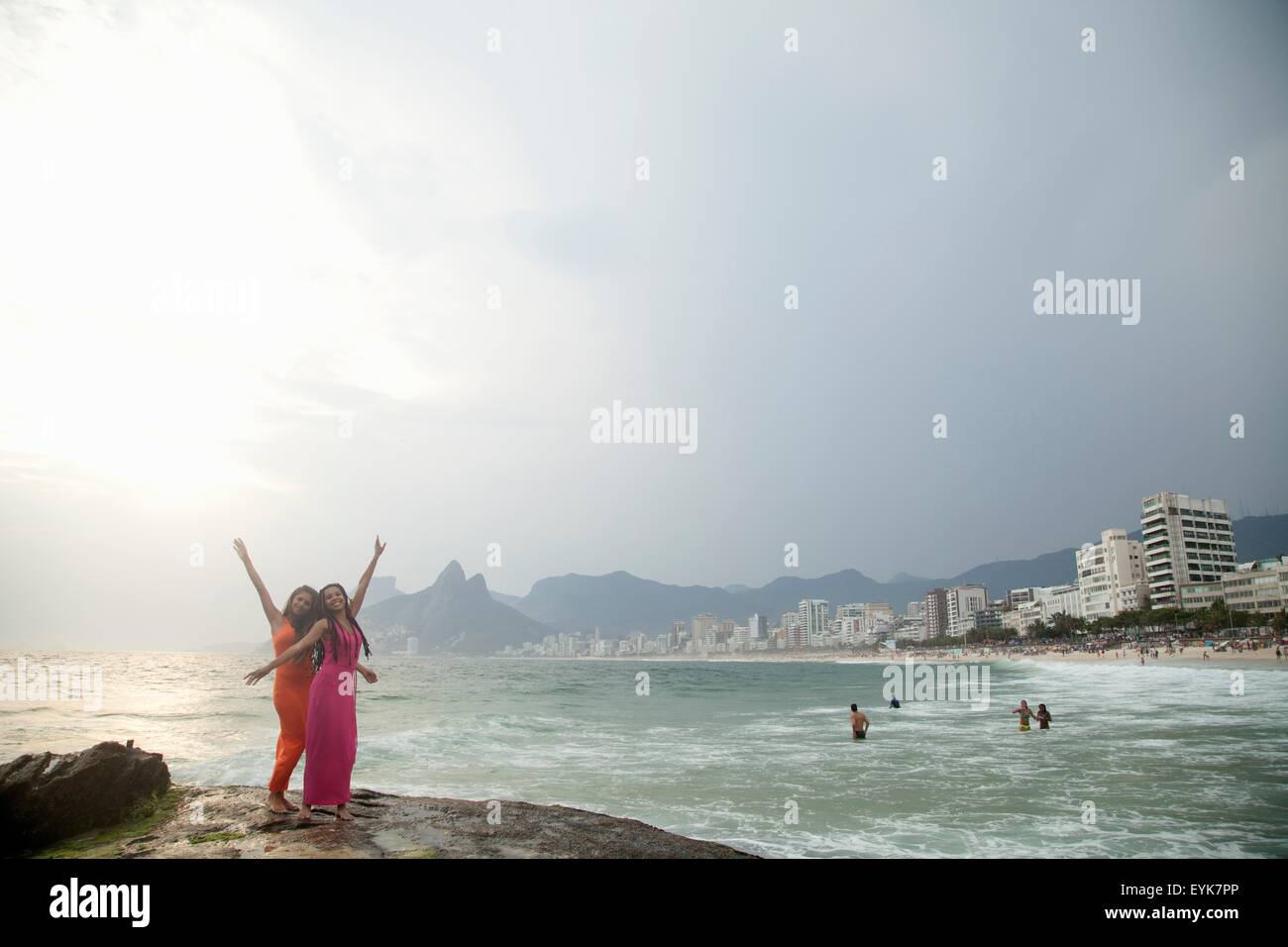 Portrait of two young women with arms raised on Ipanema beach, Rio De ...